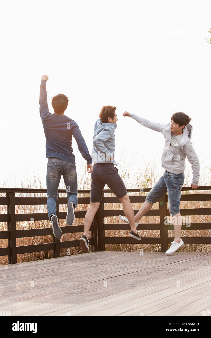 Back appearance of three men behind the fence at the park Stock Photo ...