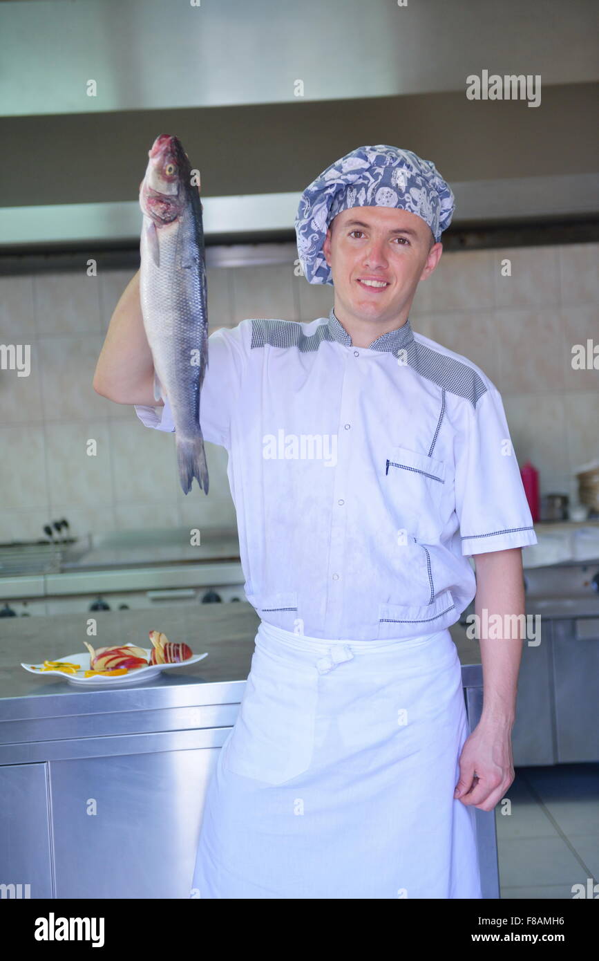 Handsome chef dressed in white uniform decorating pasta salad and ...