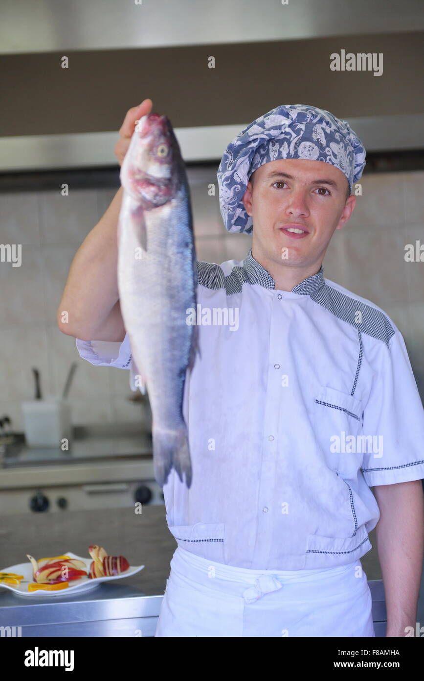 Handsome chef dressed in white uniform decorating pasta salad and ...
