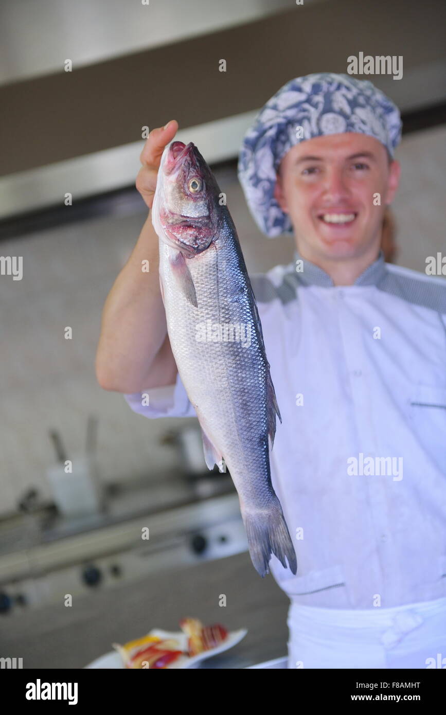 Handsome chef dressed in white uniform decorating pasta salad and ...