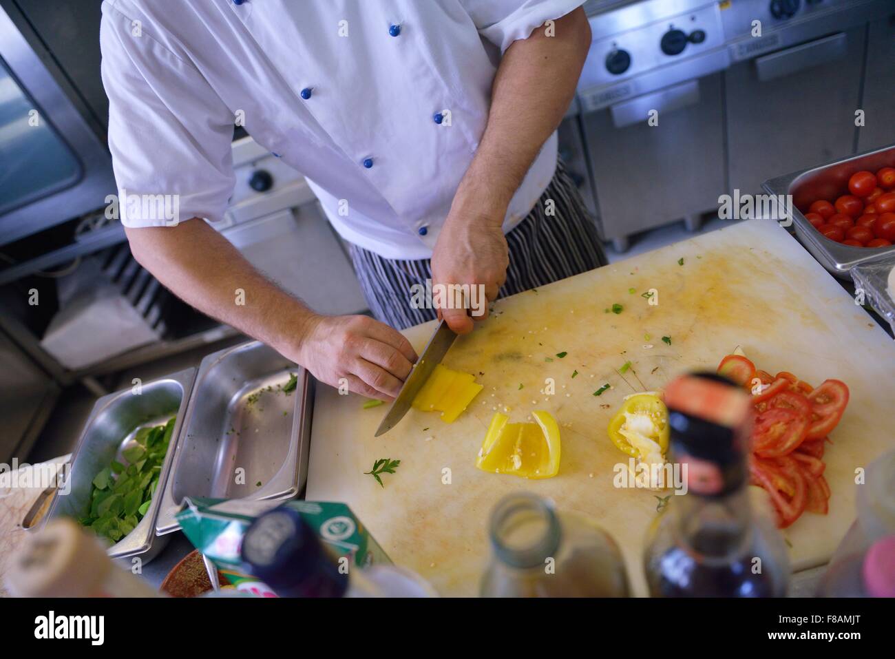 Handsome chef dressed in white uniform decorating pasta salad and ...