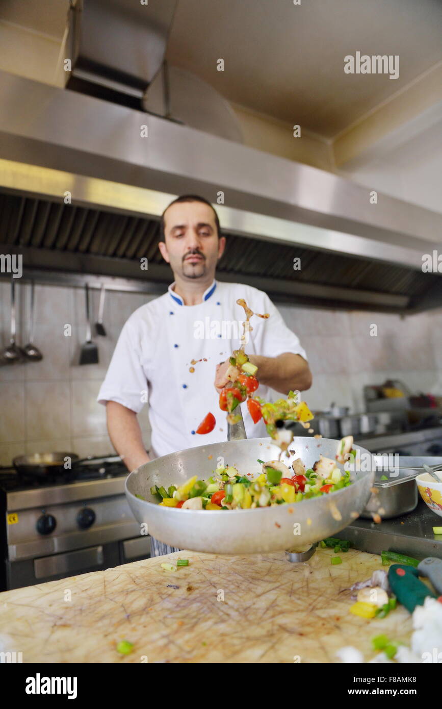 Handsome chef dressed in white uniform decorating pasta salad and ...