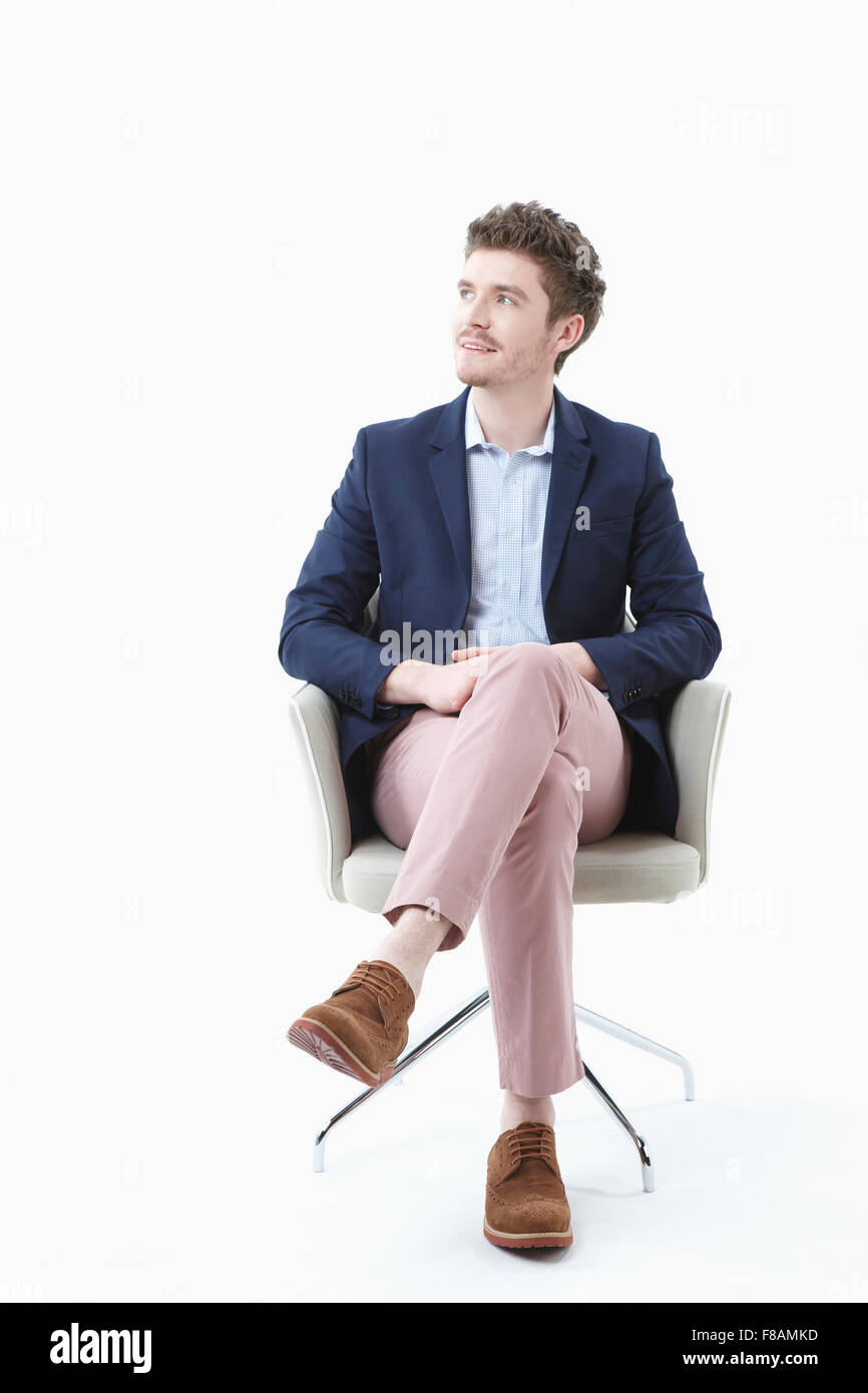 Businessman sitting on chair with his legs crossed and his hands on his ...