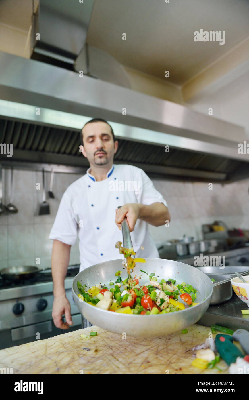 Handsome chef dressed in white uniform decorating pasta salad and ...