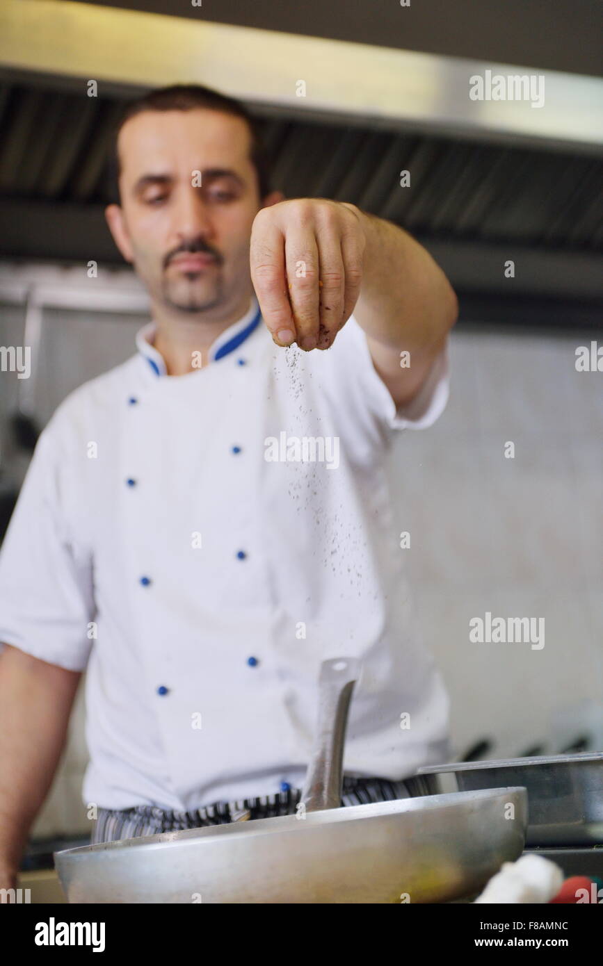 Handsome chef dressed in white uniform decorating pasta salad and ...