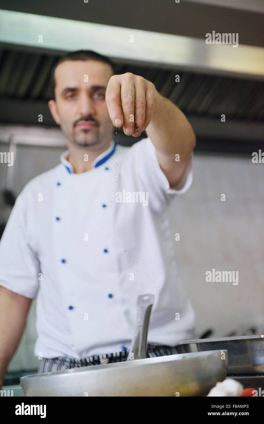 Handsome chef dressed in white uniform decorating pasta salad and ...