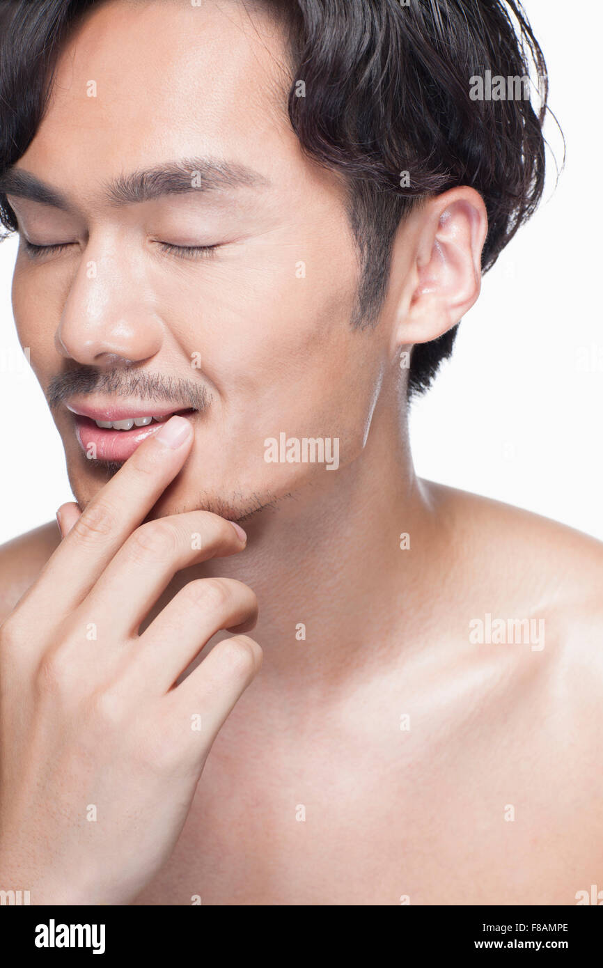 Portrait of young Asian man touching his chin with closed eyes Stock ...
