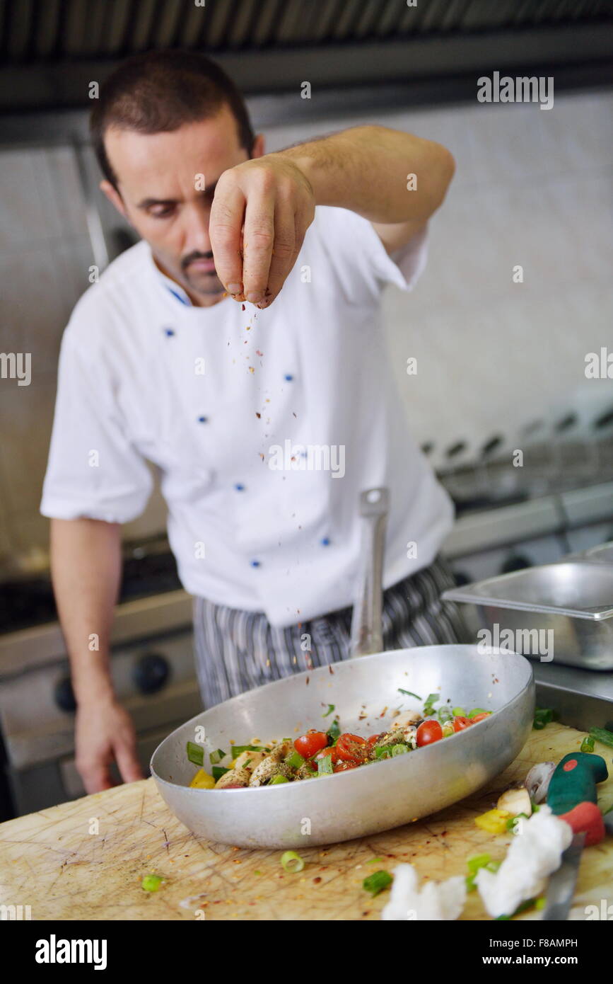 Handsome chef dressed in white uniform decorating pasta salad and ...