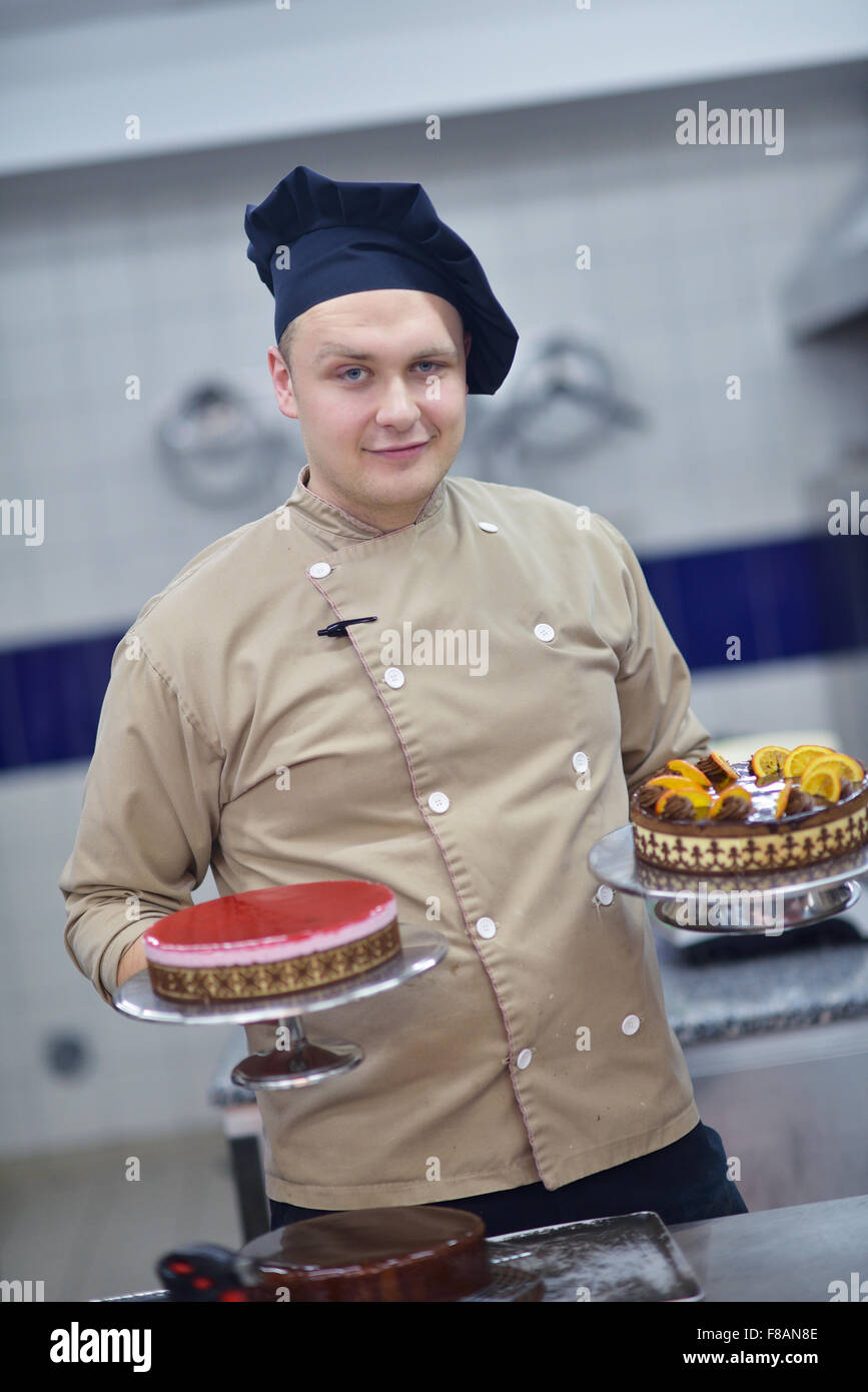 Closeup of a concentrated male pastry chef decorating dessert cake food ...