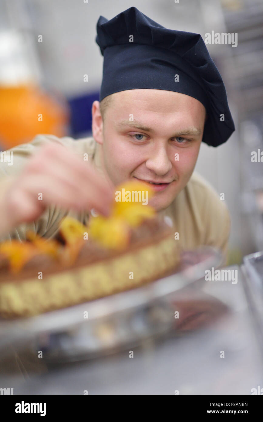 Closeup of a concentrated male pastry chef decorating dessert cake food ...