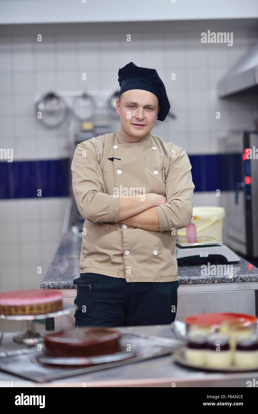 Closeup of a concentrated male pastry chef decorating dessert cake food ...