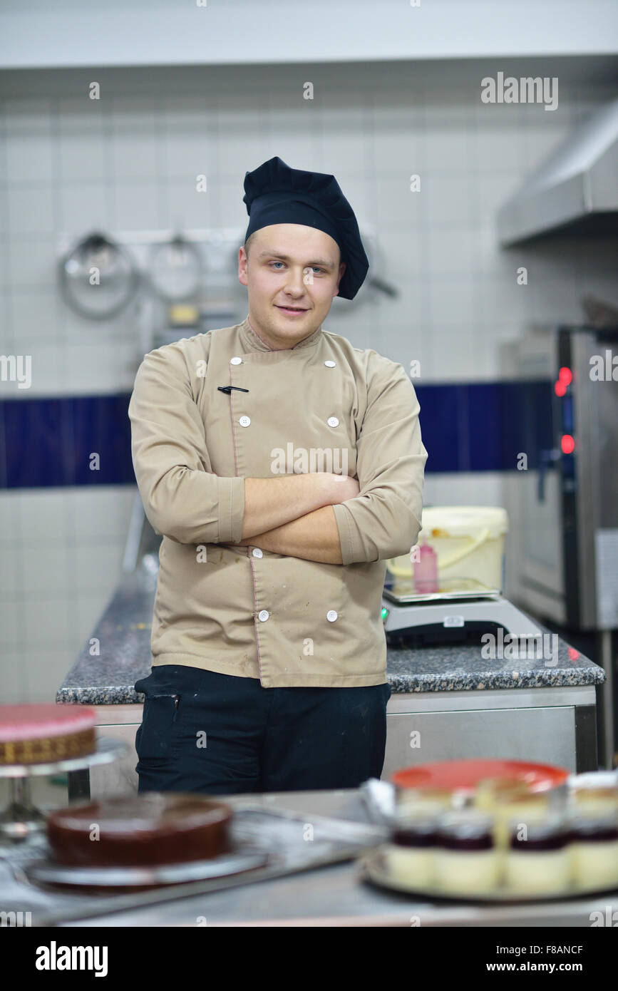 Closeup of a concentrated male pastry chef decorating dessert cake food ...