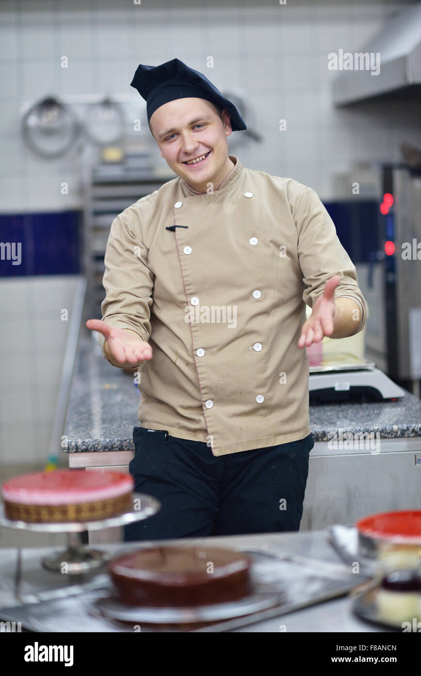 Closeup of a concentrated male pastry chef decorating dessert cake food ...