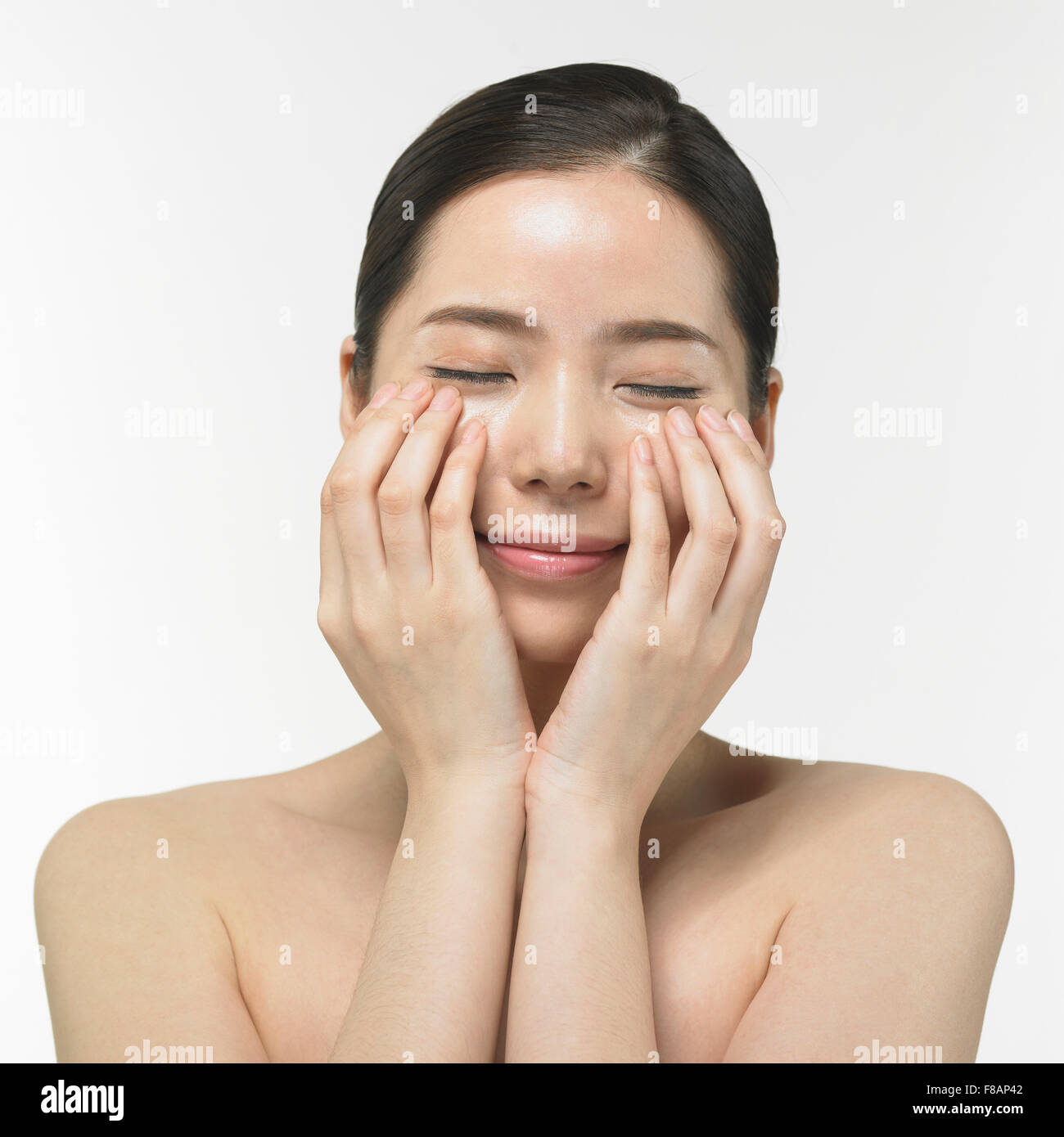 Portrait of Korean woman wrapping her cheeks with hands closing eyes ...