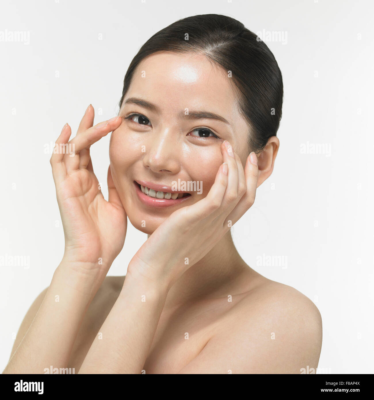 Portrait of Korean woman touching the corners of her eyes with fingers ...