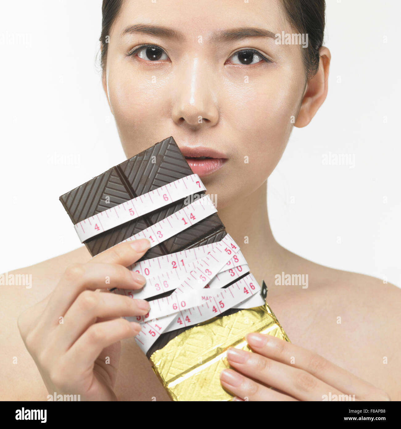 Portrait of Korean woman showing chocolate wrapped with tape measure ...