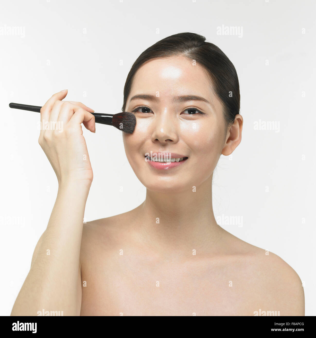 Portrait of Korean woman brushing her face starig at front with a big ...