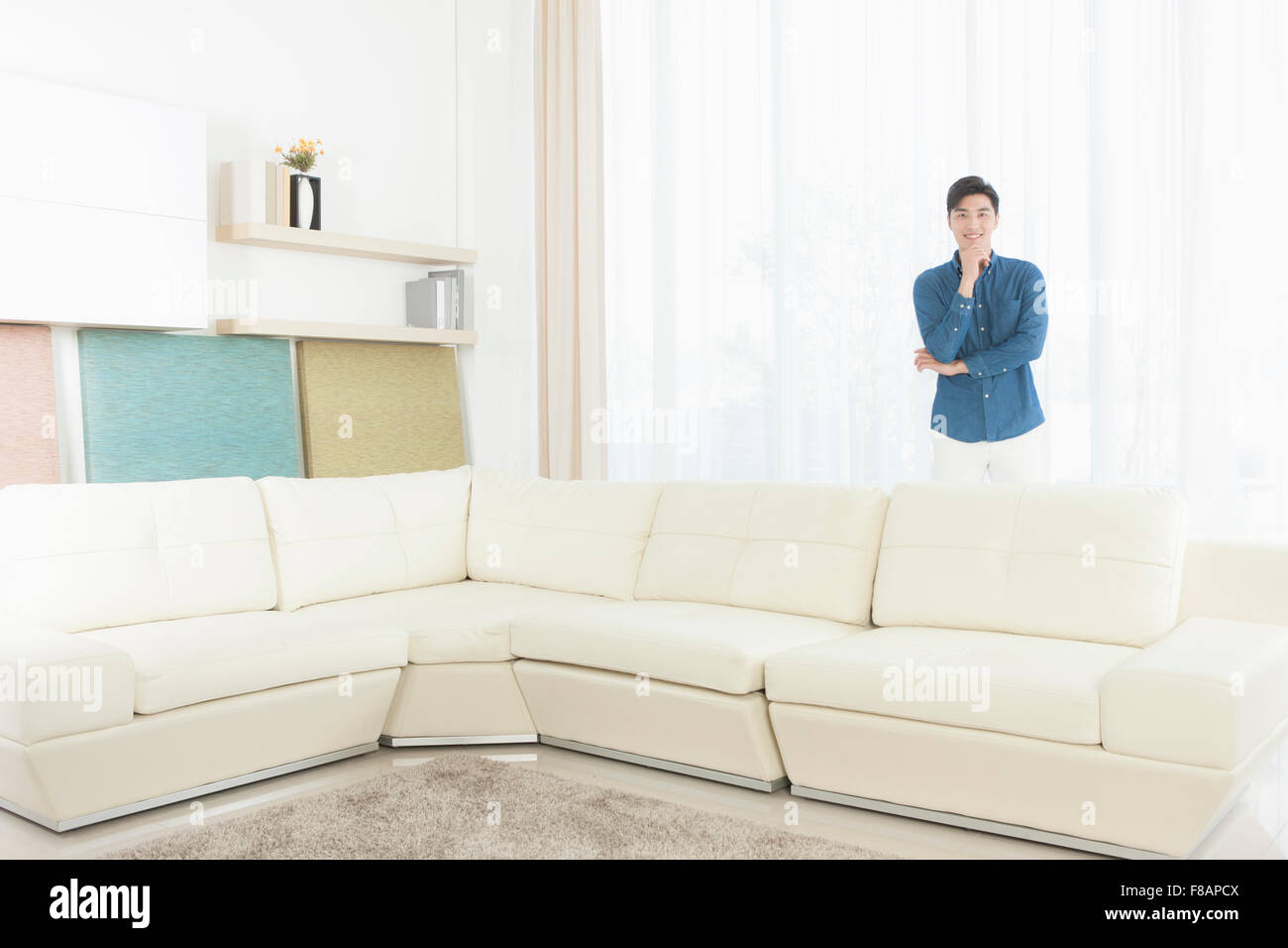 Smiling young man staring at front with his chin on his hand in front ...