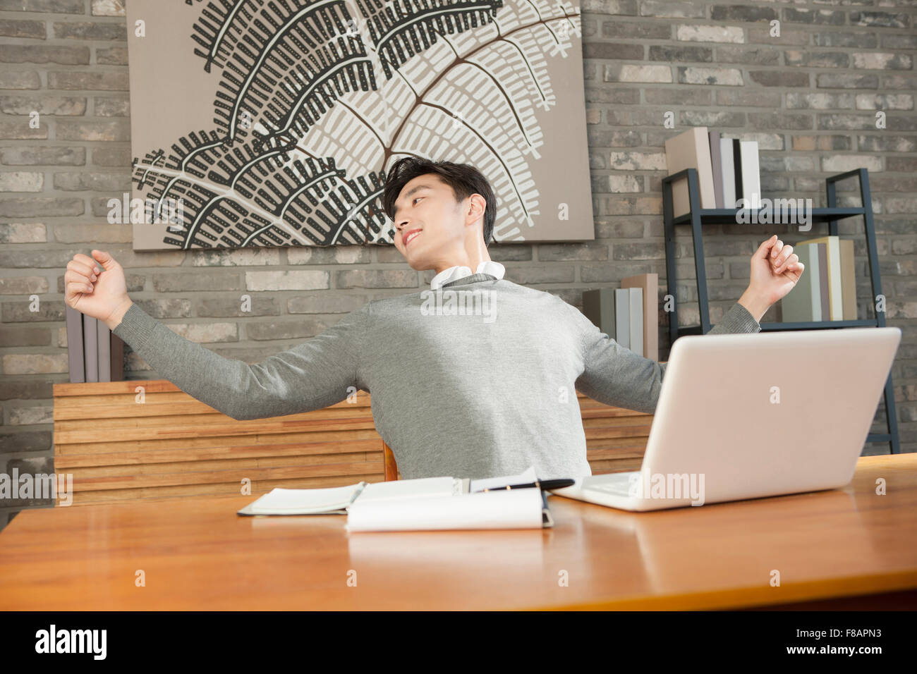 Portrait of smiling young businessman stretching with notebook computer ...
