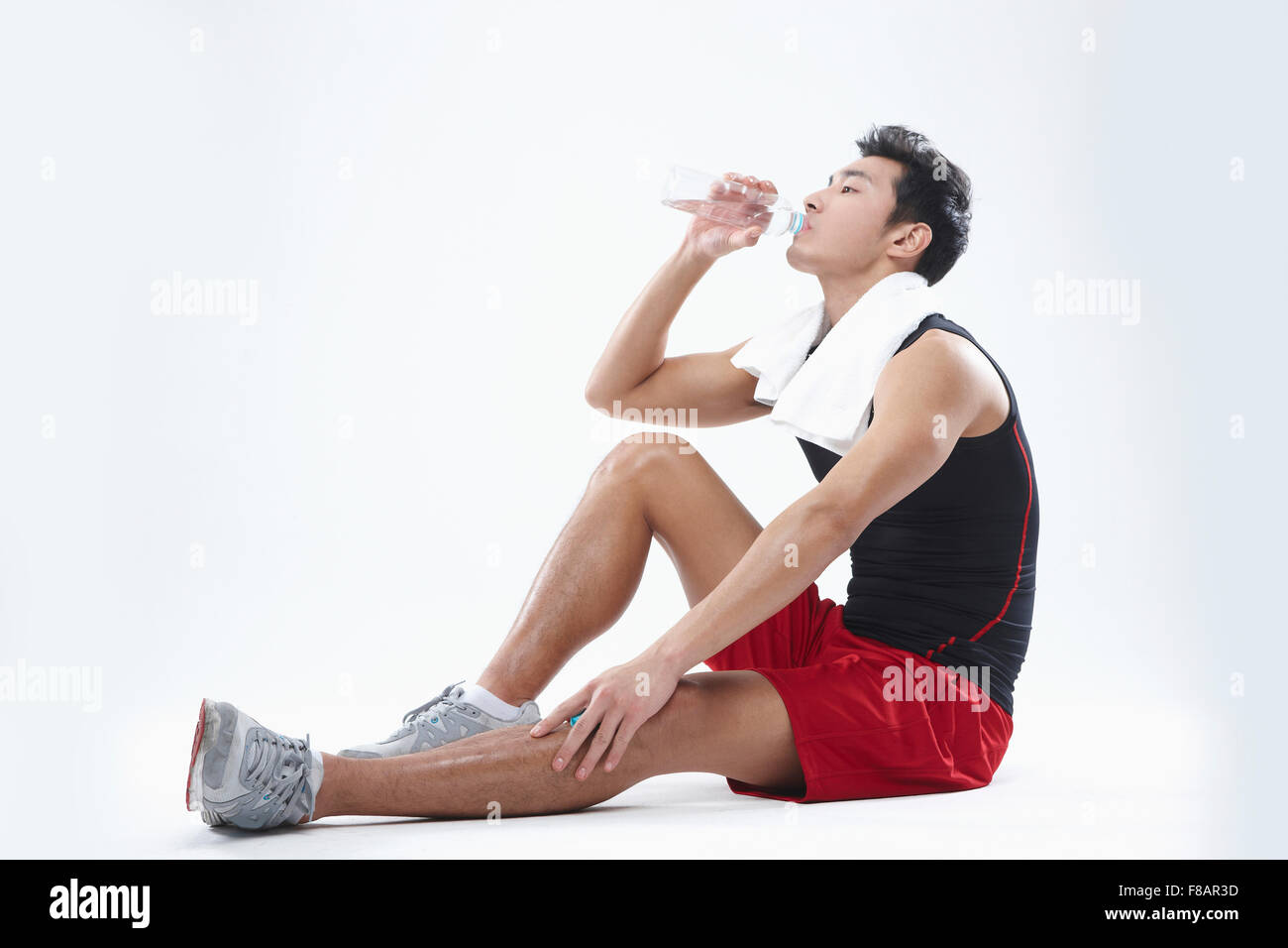 Man in sportswear sitting drinking water raising head Stock Photo - Alamy