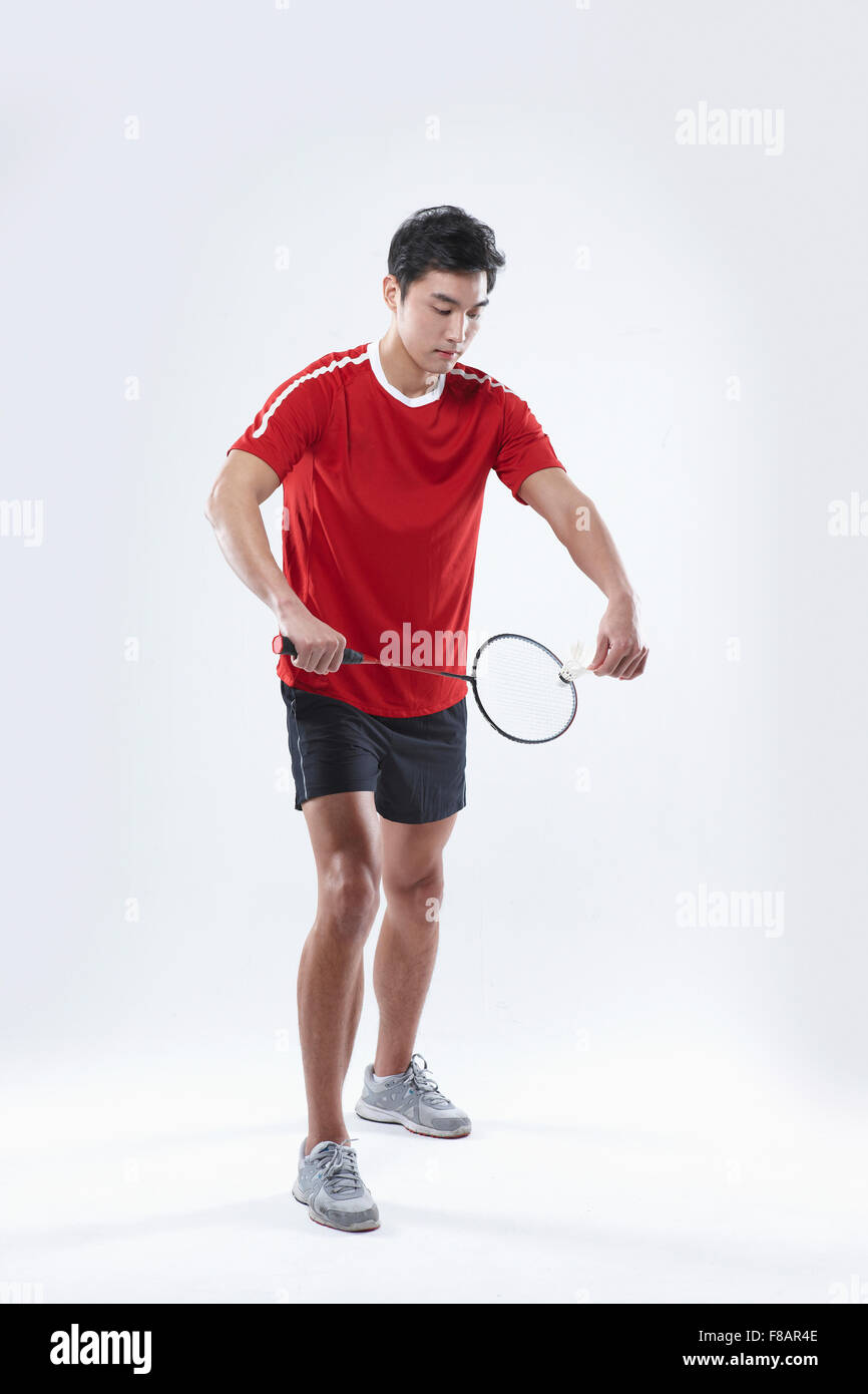 Man holding a racket and a shuttlecock looking down Stock Photo - Alamy