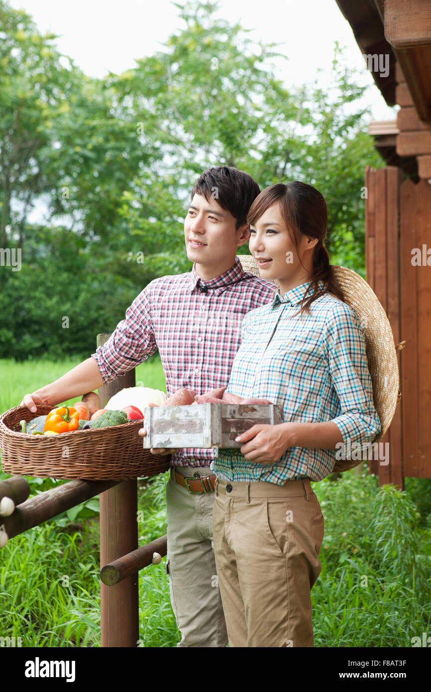 Loving smiling couple standing with fresh vegetables looking up in the ...
