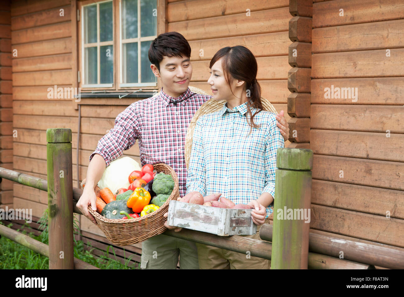 Loving smiling couple standing face to face with fresh vegetables in ...