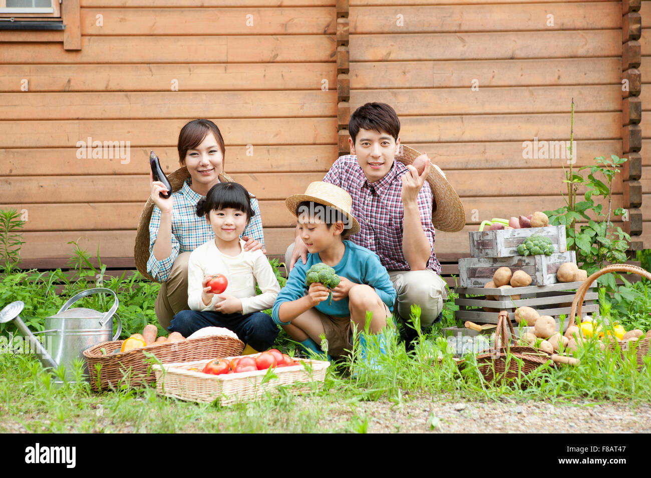 Smiling family sitting with fresh vegetables in country house yard ...