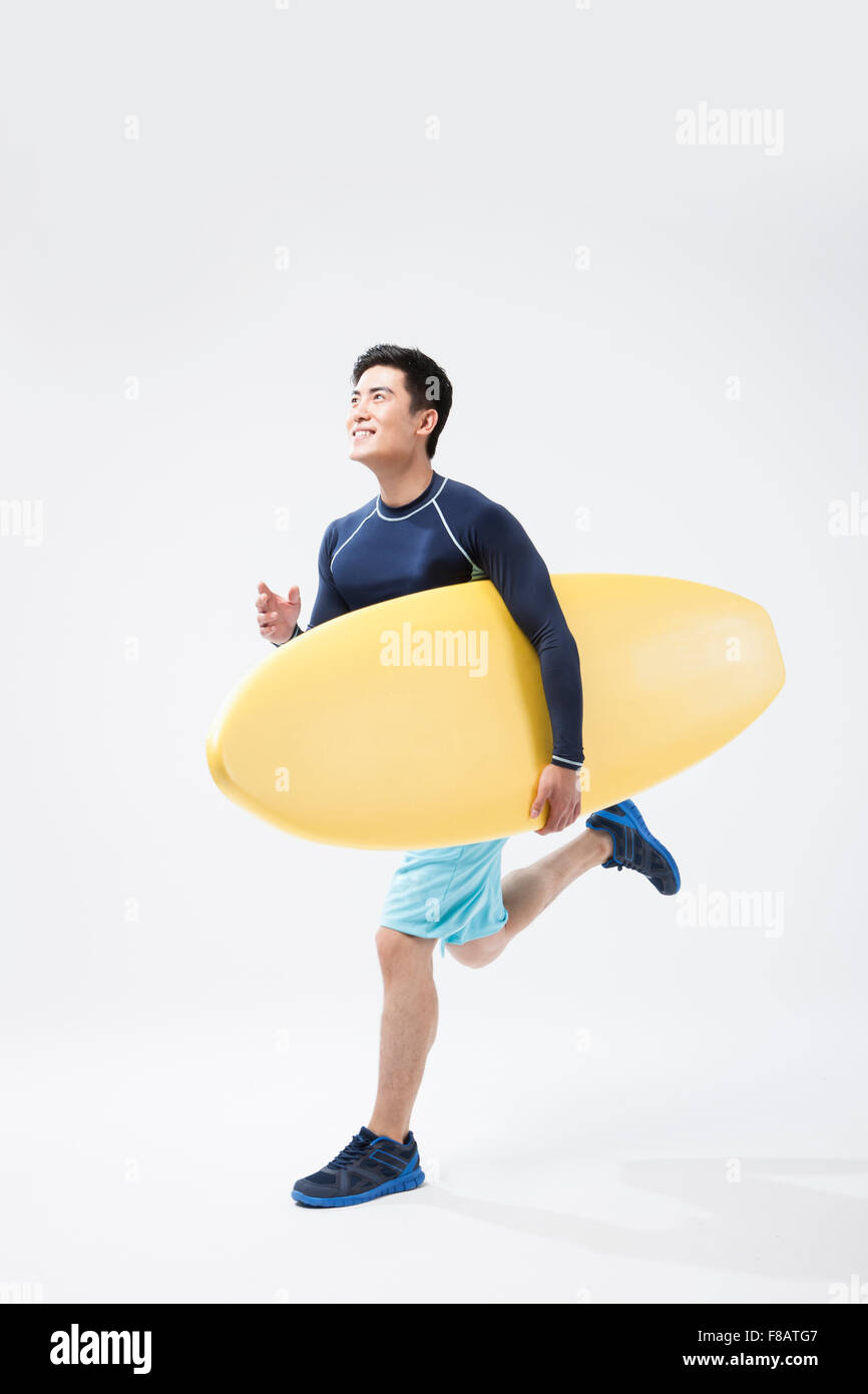 Man running with a surfing board looking up Stock Photo - Alamy
