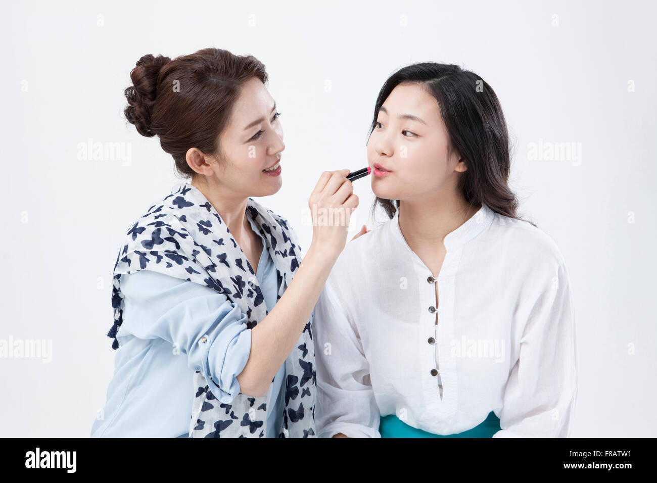 Portrait of mother and daughter applying lipstick Stock Photo - Alamy