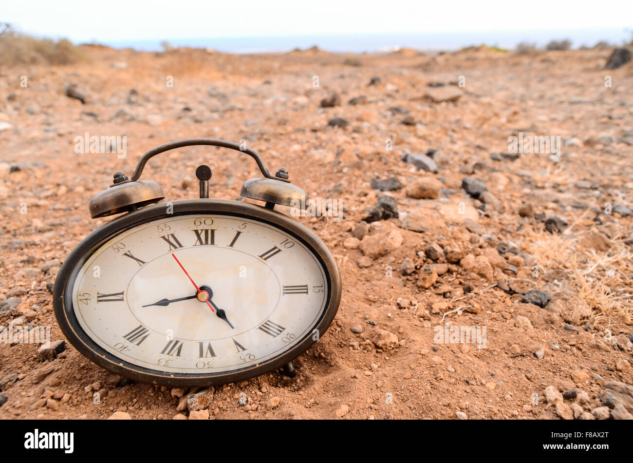 Classic Analog Clock In The Sand Stock Photo - Alamy