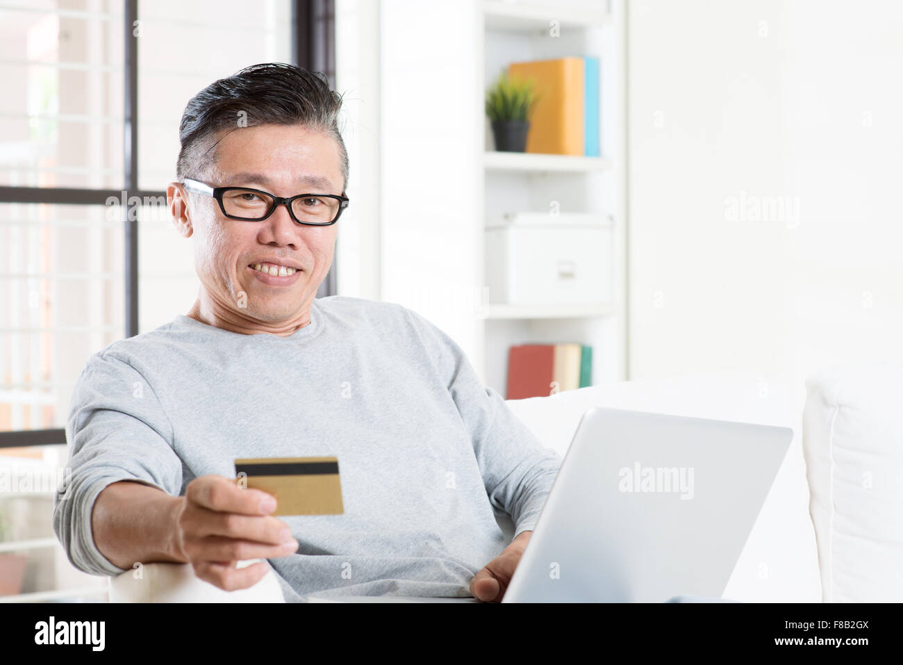 Portrait of 50s mature Asian man using computer paying bill with credit ...