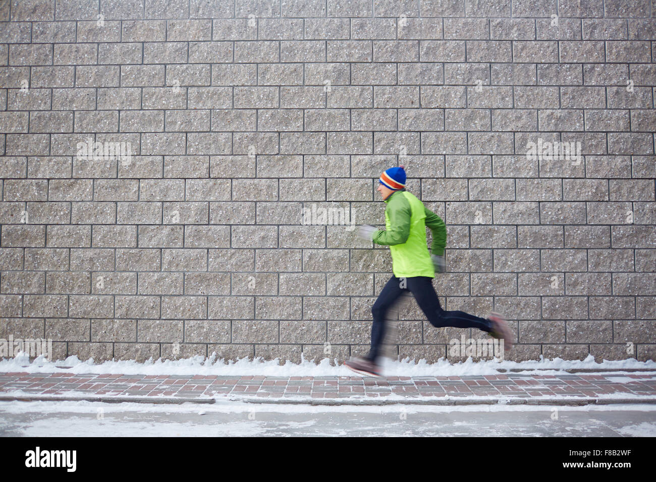Young sportsman jogging along brick wall in winter Stock Photo - Alamy