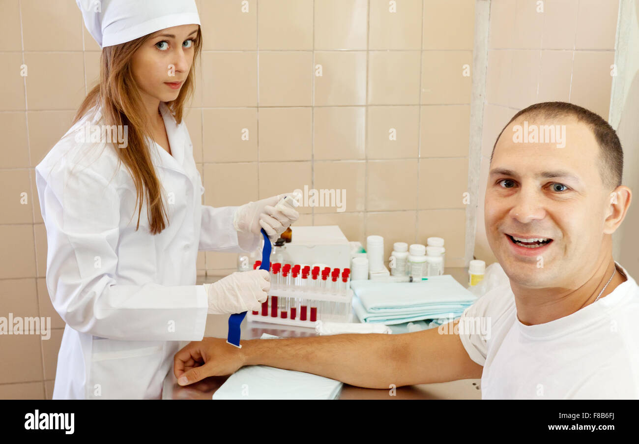 young nurse taking blood sample from patient in clinic. Focus on man ...