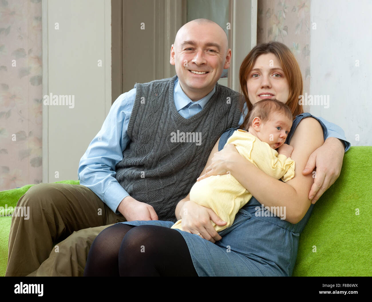Family of three with newborn baby on sofa Stock Photo - Alamy