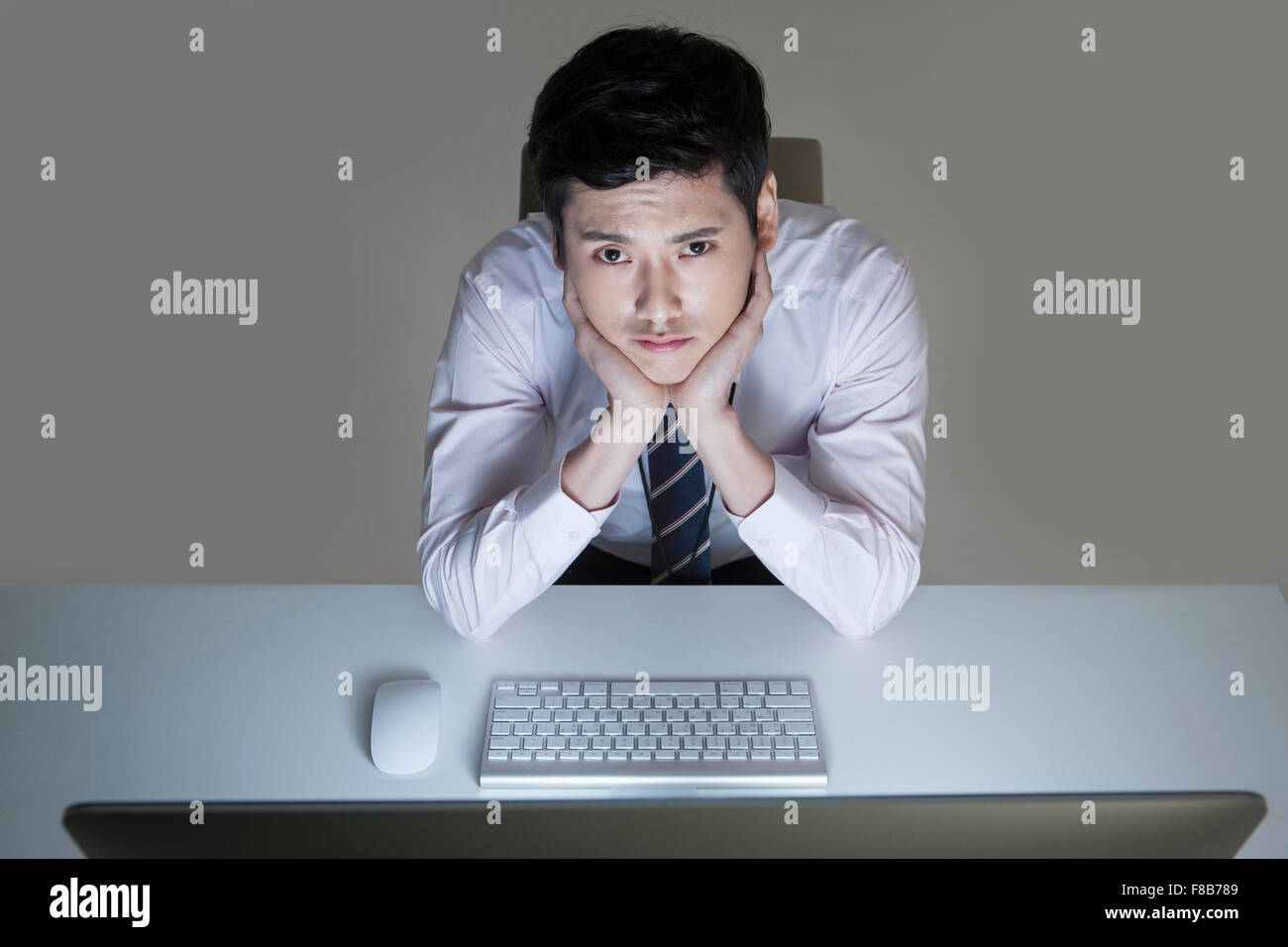 High angle of business man with frown face seated at desk working on ...