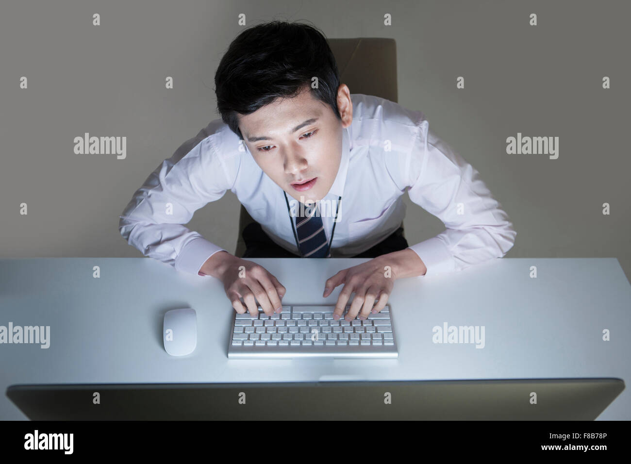 Tired business man seated at desk typing on keyboard Stock Photo - Alamy