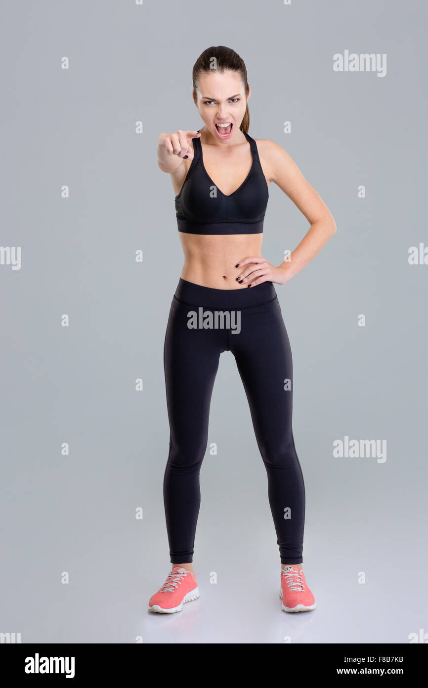 Mad angry young fitness woman in sportwear screaming and pointing on ...
