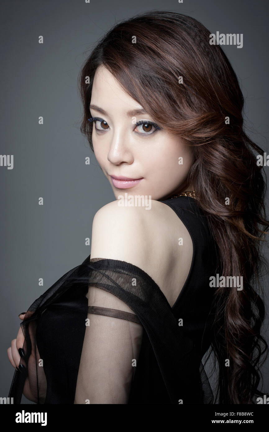 Asian woman with long wavy hair staring forward and putting lace cloth ...