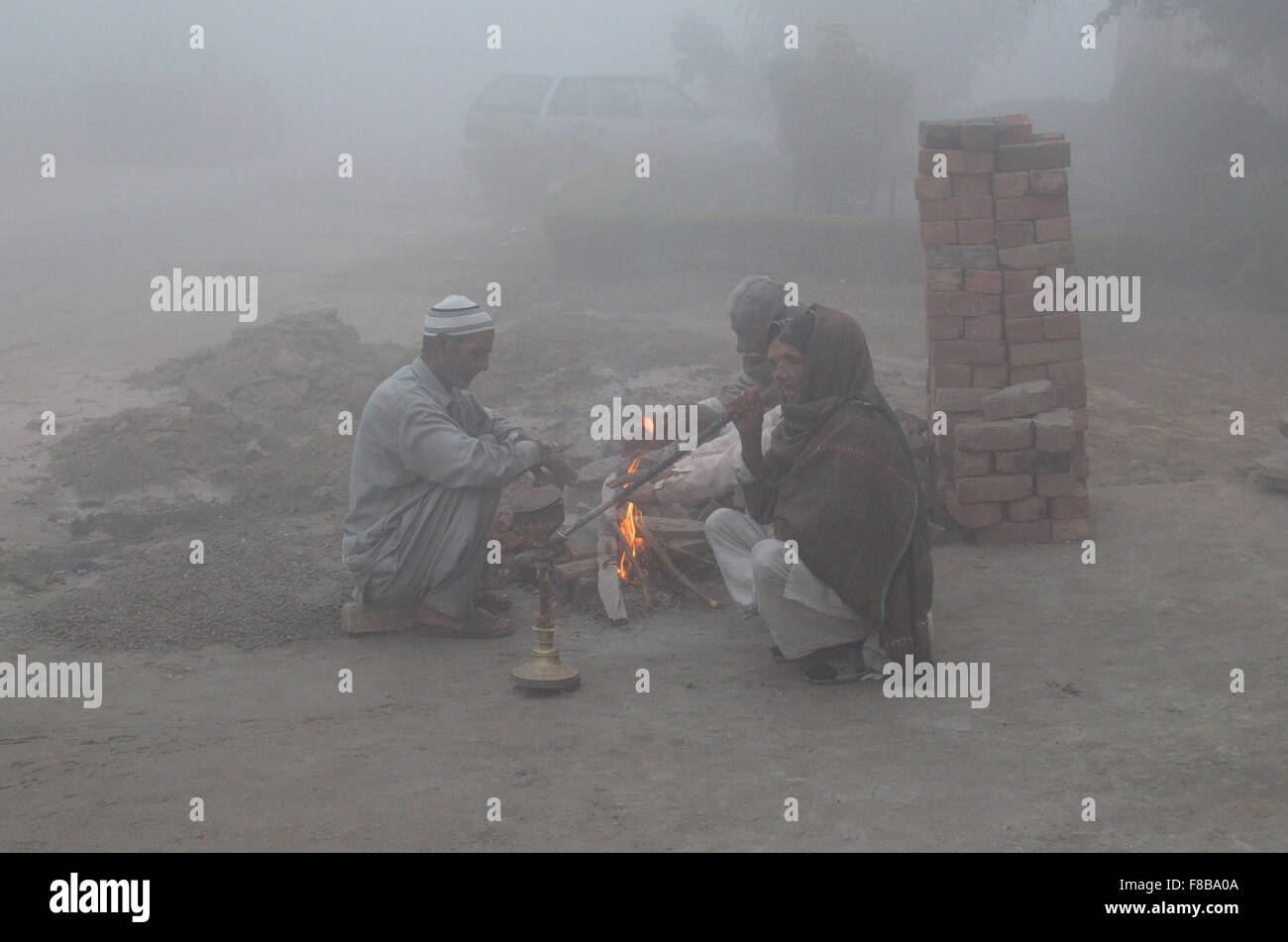Lahore. 8th Dec, 2015. Pakistani laborers warm themselves by a fire in ...