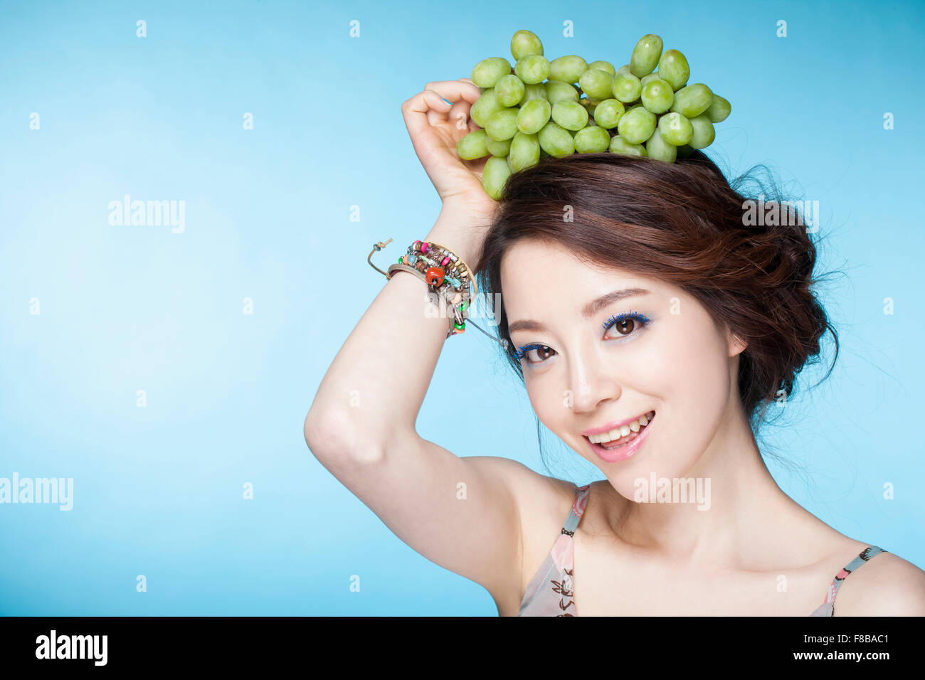 Woman smiling and putting grapes on her head Stock Photo - Alamy