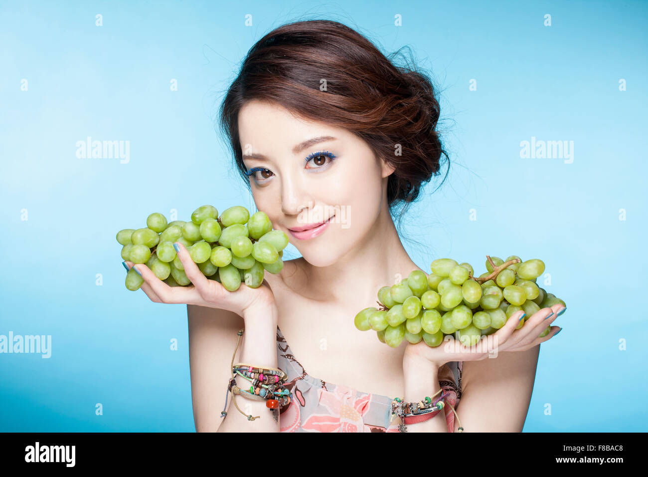 Woman in summer wear with full make-up holding grapes in both hands Stock Photo - Alamy
