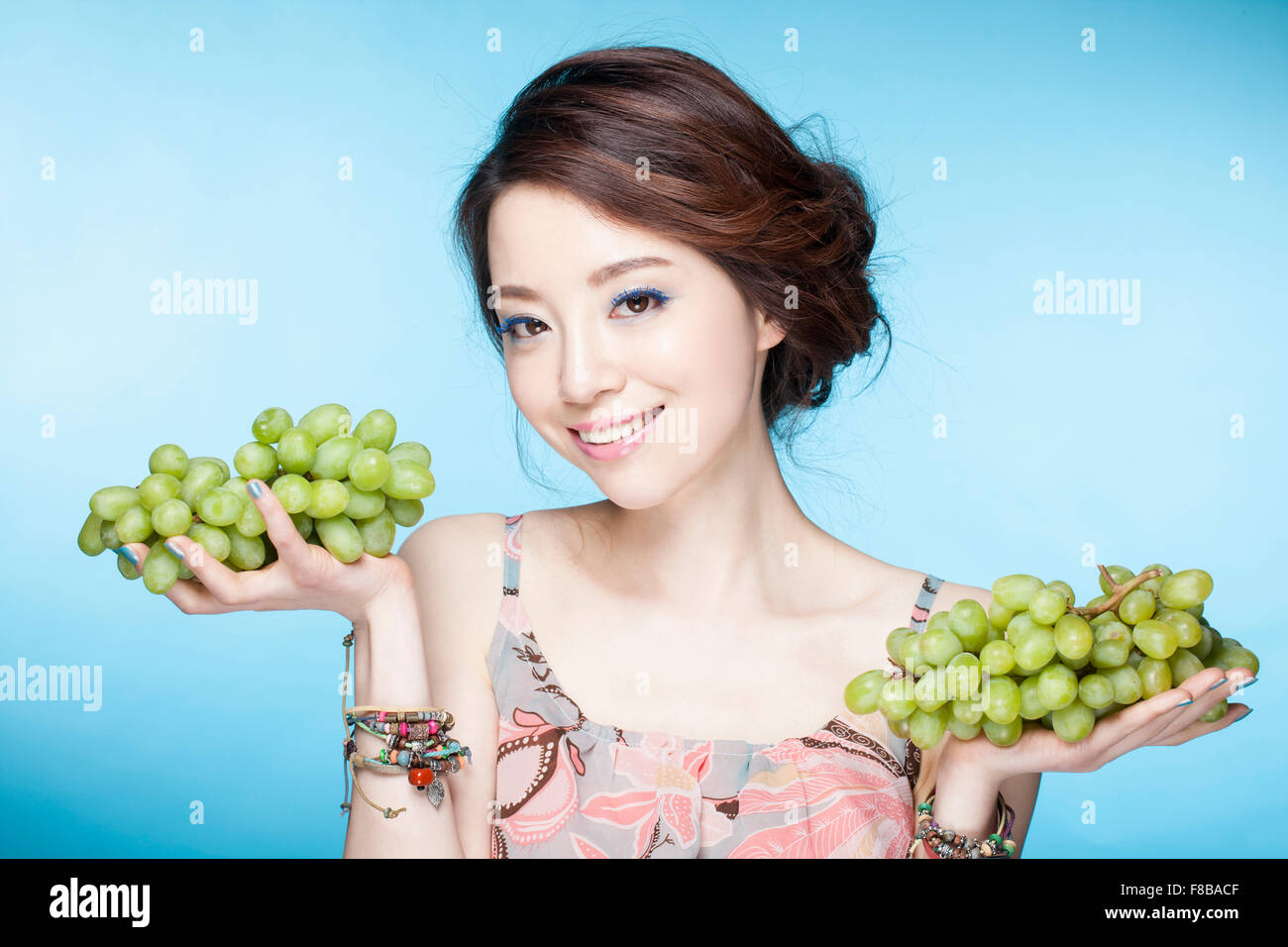 Woman in summer wear with full make-up holding grapes in both hands Stock Photo - Alamy