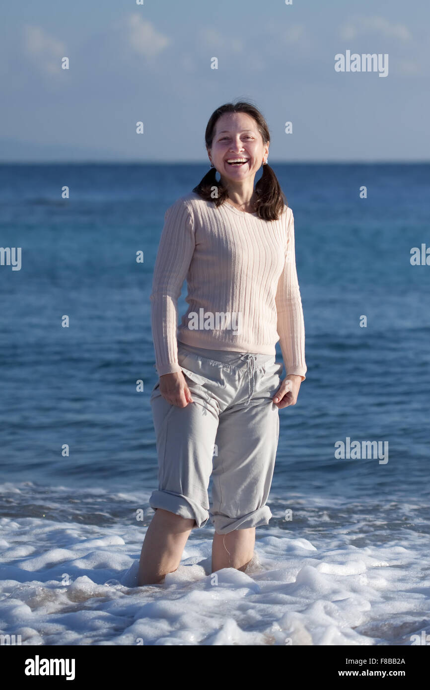 Happy mature woman stands at sea wave Stock Photo - Alamy