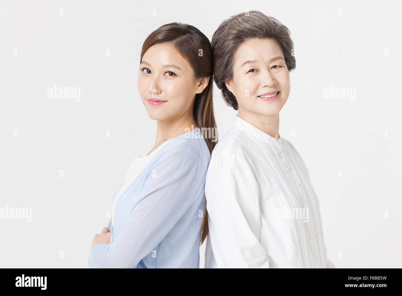 Mother and grown up daughter standing back to back each other and ...