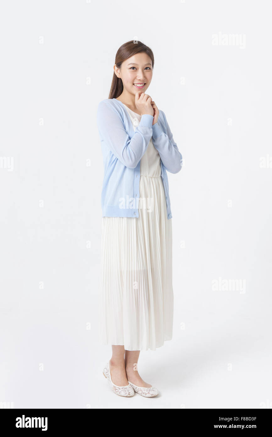 Woman in white dress and blue cardigan staring forward with her hands ...