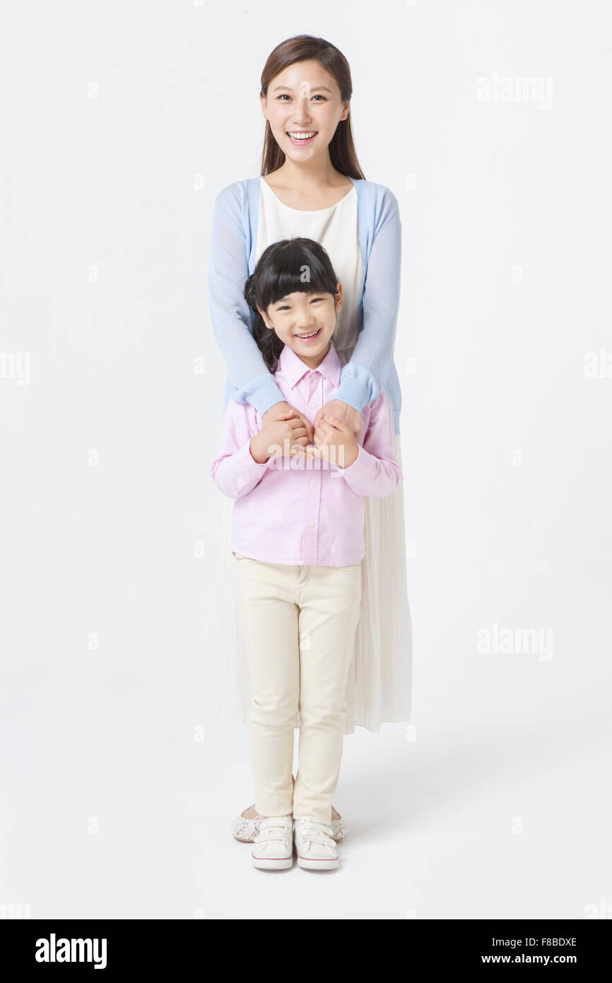 Mother holding her daughter's hands from behind both staring forward ...