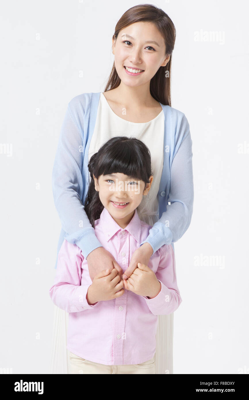 Mother holding her daughter's hands from behind both staring forward ...