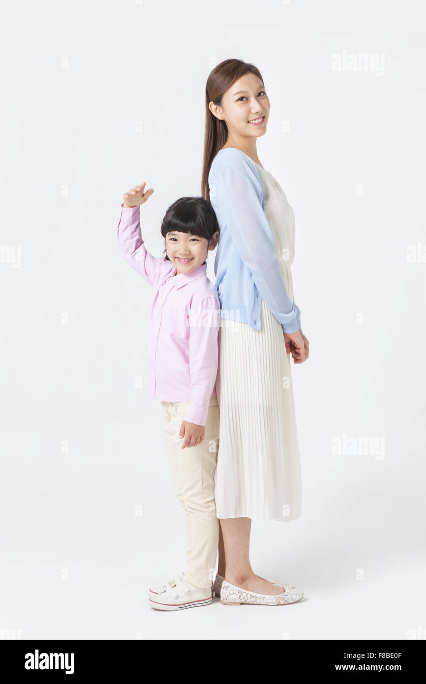 Mother And Daughter Standing Back To Back Each Other And Smiling