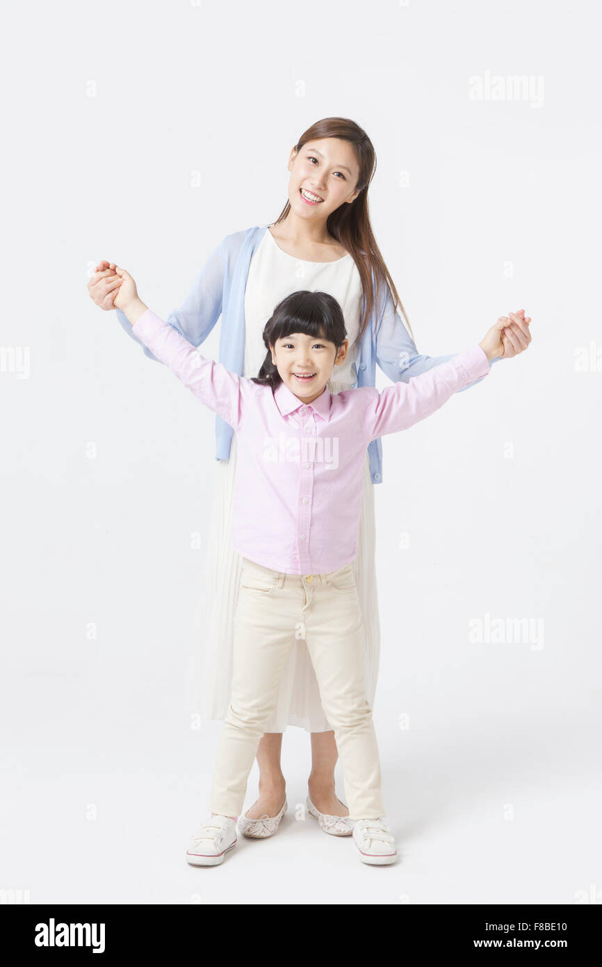 Mother standing behind the daughter and holding her hands and opening ...